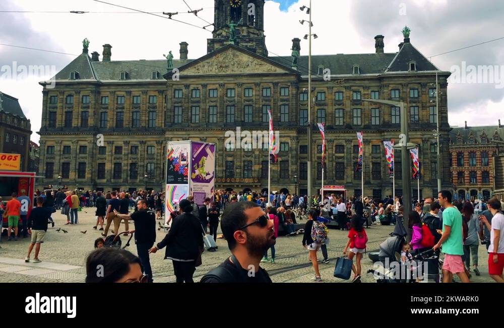 People on a crowded square of a quaint town, a building with a clock ...