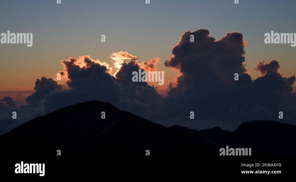 Brilliant summit dawn above flowing cloud waves, red sun disk time ...