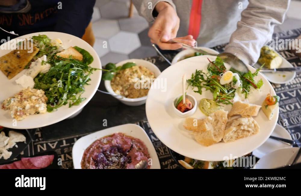 Brunch food layout in restaurant people hands put various dishes on ...