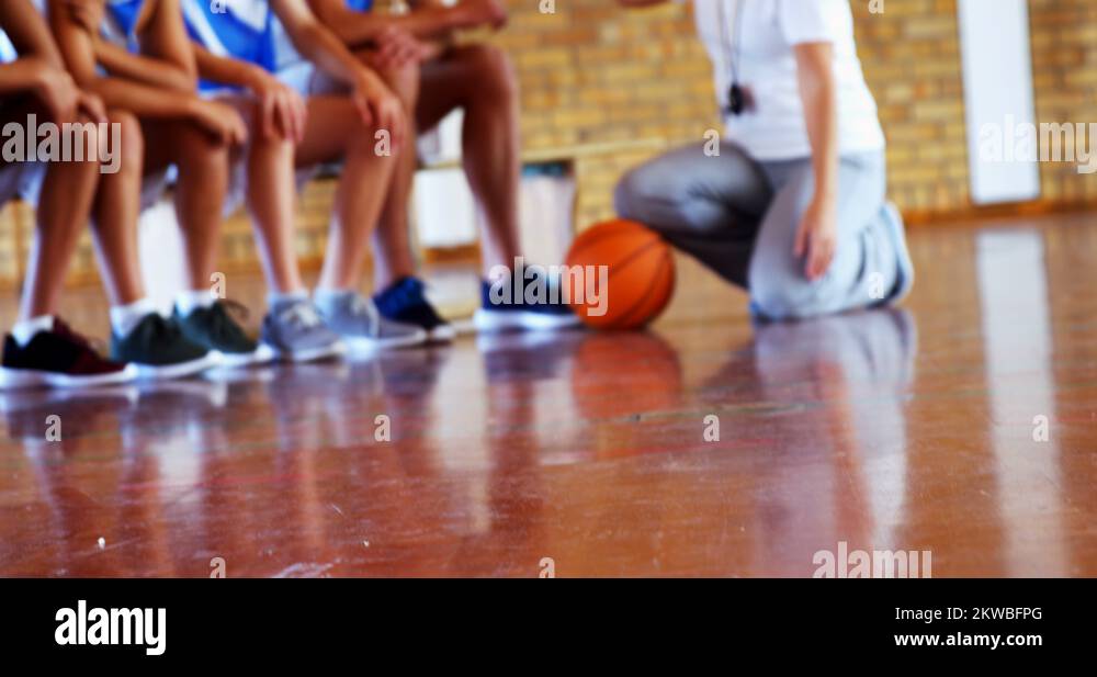 Female coach giving high five to students in basketball court Stock ...