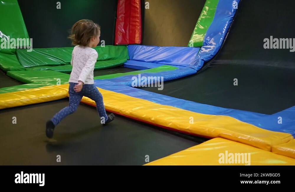 Little kid girl enjoy run and jump on trampoline playground for ...
