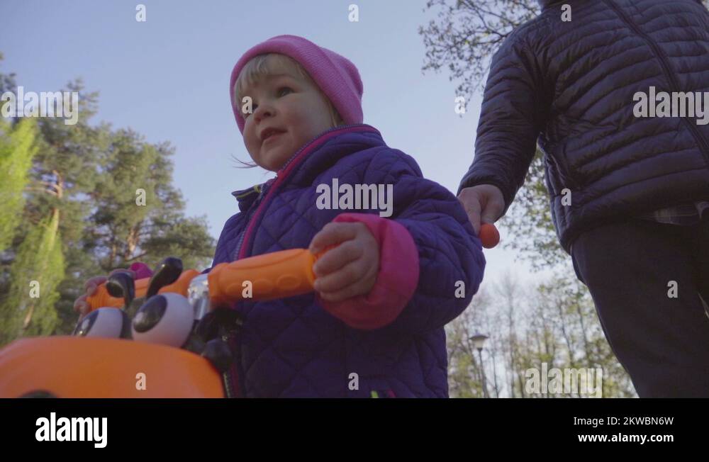 Father rolls his little girl on a scooter, low angle gimbal shot, slow ...