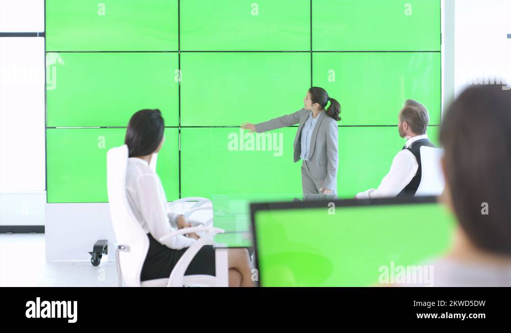 4K Business team in a meeting, interacting with large green screen ...