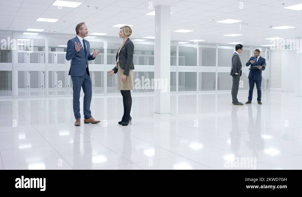 4K Business people looking around large data center with rows of server ...