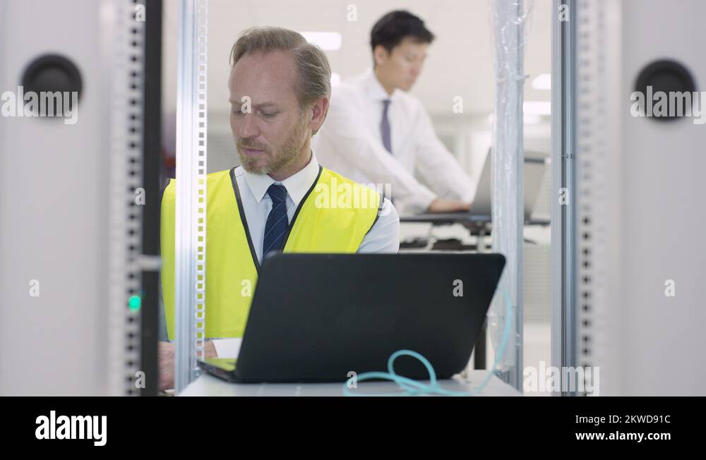 4K Technical engineer carrying out checks in a data center server room ...