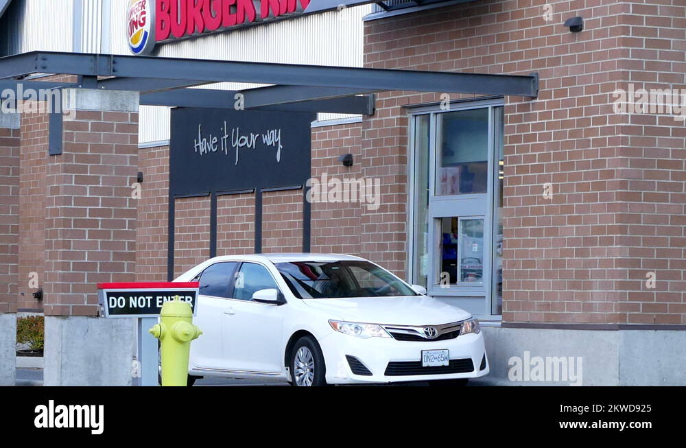 One side of Burger King drive thru with car buying food and tapping ...
