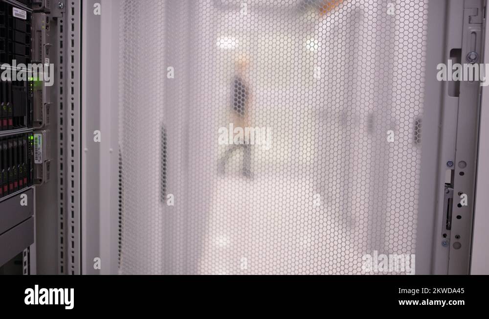 4K View through mesh door of a data cabinet in a data center with staff ...