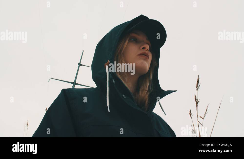 Young sleepy caucasian blonde girl in black cap and hood in front of ...