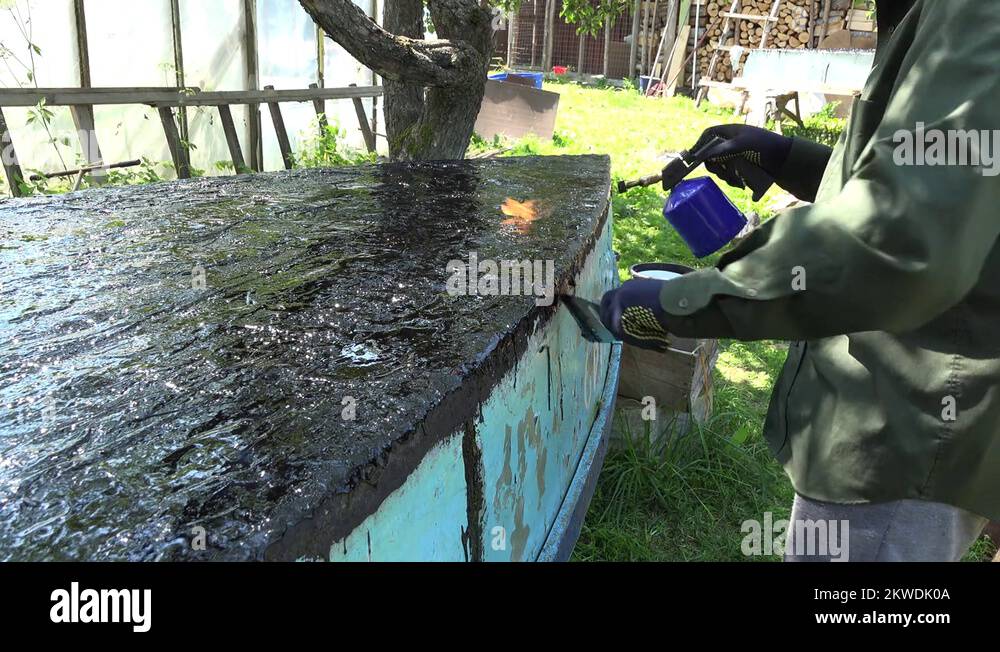 man hands with gas burner torch level tar on boat bottom in big flame ...