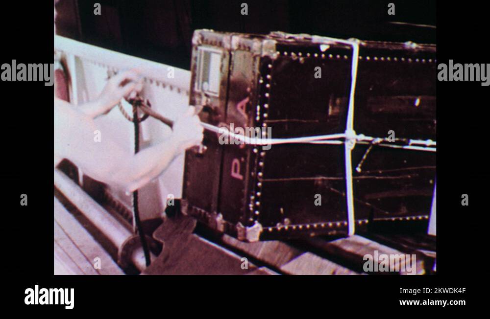 UNITED STATES: 1955: Ship's porter pulls luggage from conveyor belt on ...