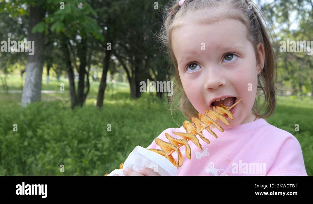 Little child girl portrait eating a street food potato snacks walking ...
