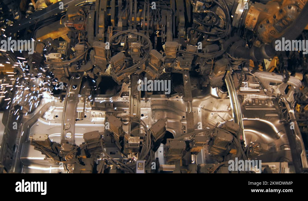 robots weld car body on a car factory, top view, sparks and lights ...