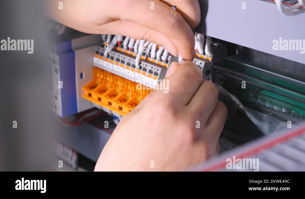 The close-up of the unrecognised person assembling the connections in ...