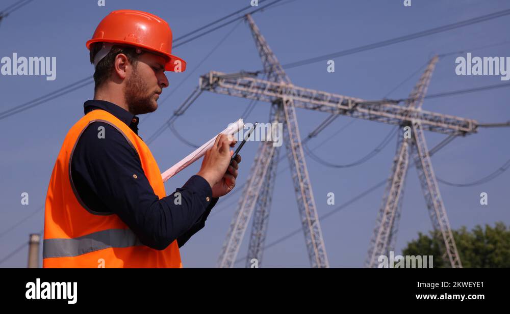 Engineer Man Work on Touchpad Device Look Up at a Pylon Structure ...