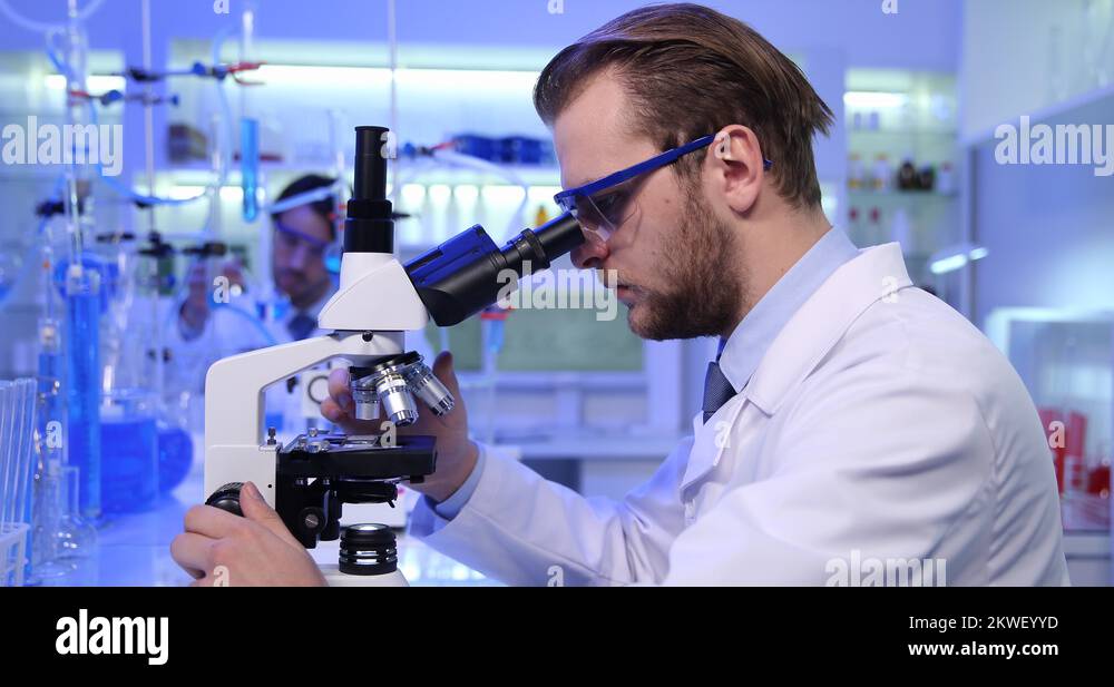 Scientist Researcher Man Looking in Microscope Checking Microscopic ...