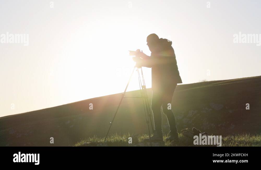 The photographer shooting with camera and tripod on the top of the hill ...
