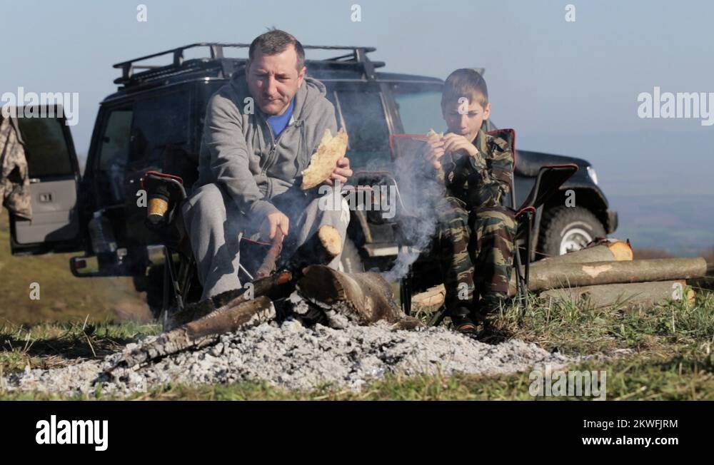 Father and son eating roasted bread next to campfire Stock Video ...