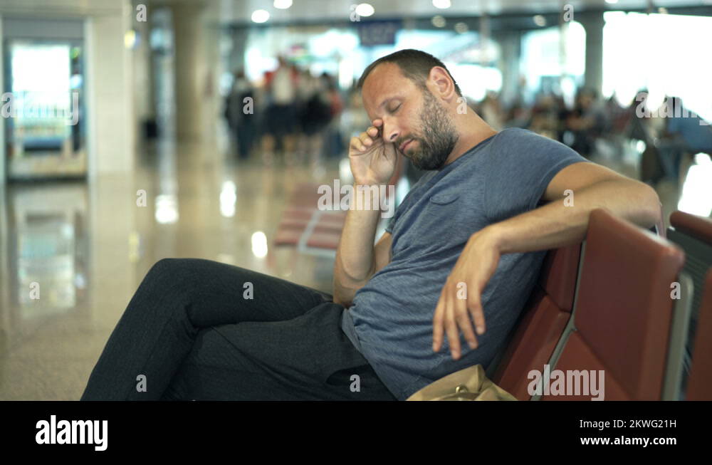 Tired man yawning and falling asleep while waiting for plane at the ...