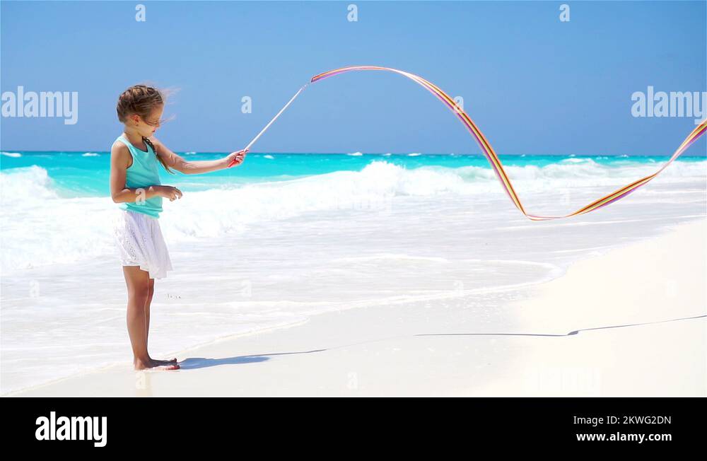 Adorable little girl playing with gymnastic ribbon on the beach. SLOW ...