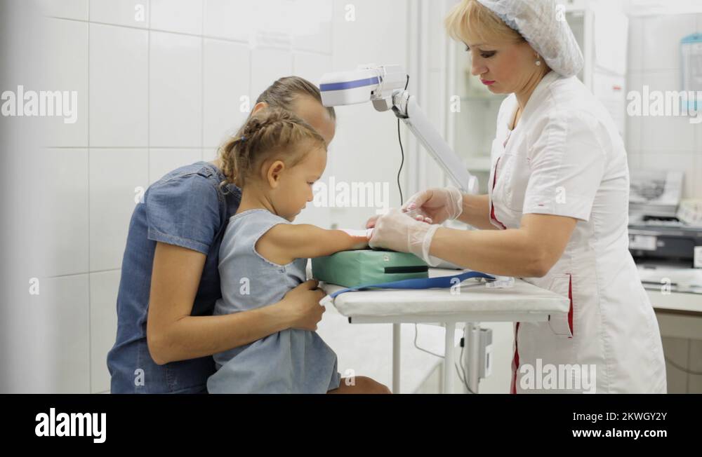 Little girl with mother in hospital. Nurse taking girl's venous blood ...