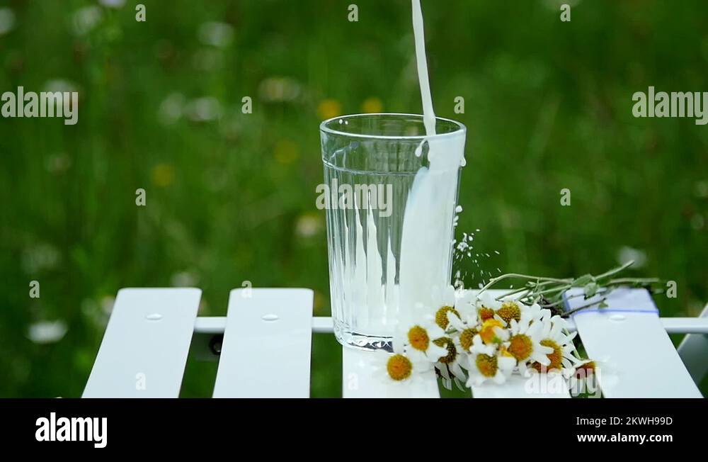 Close-up. Slowing down. Pour milk into a glass beaker. Beside lies a ...