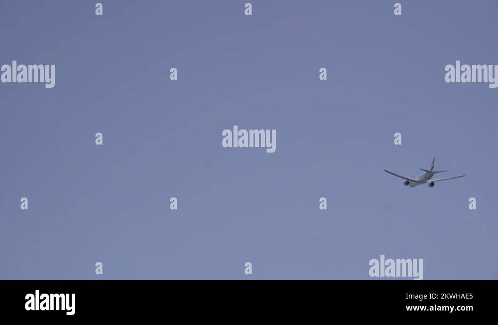 An airliner is flying away up in the blue sky. From bottom to top view ...