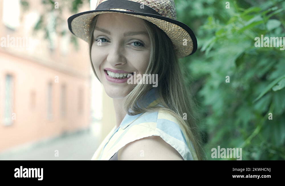 Pretty girl touching her long hair and smiling to the camera, steadycam ...