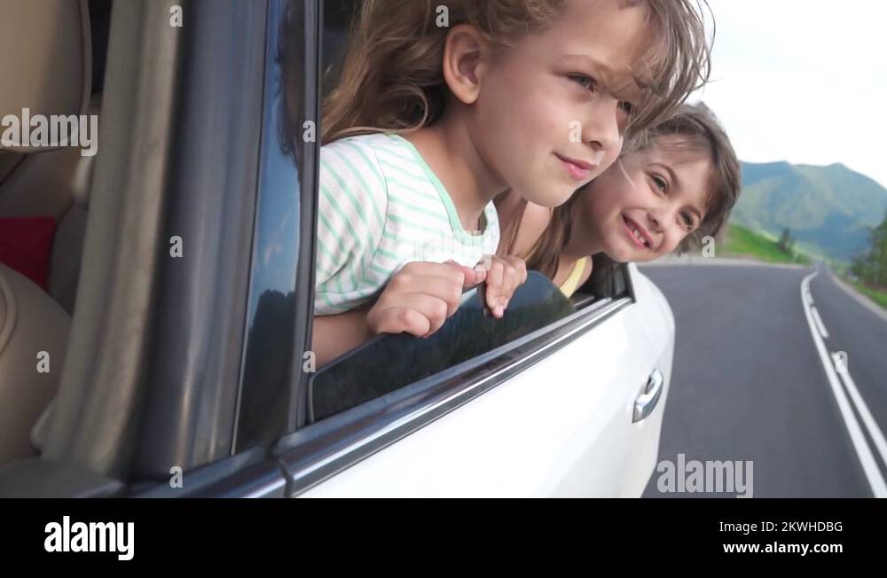carefree children leaned out the car window and smiling. two little ...