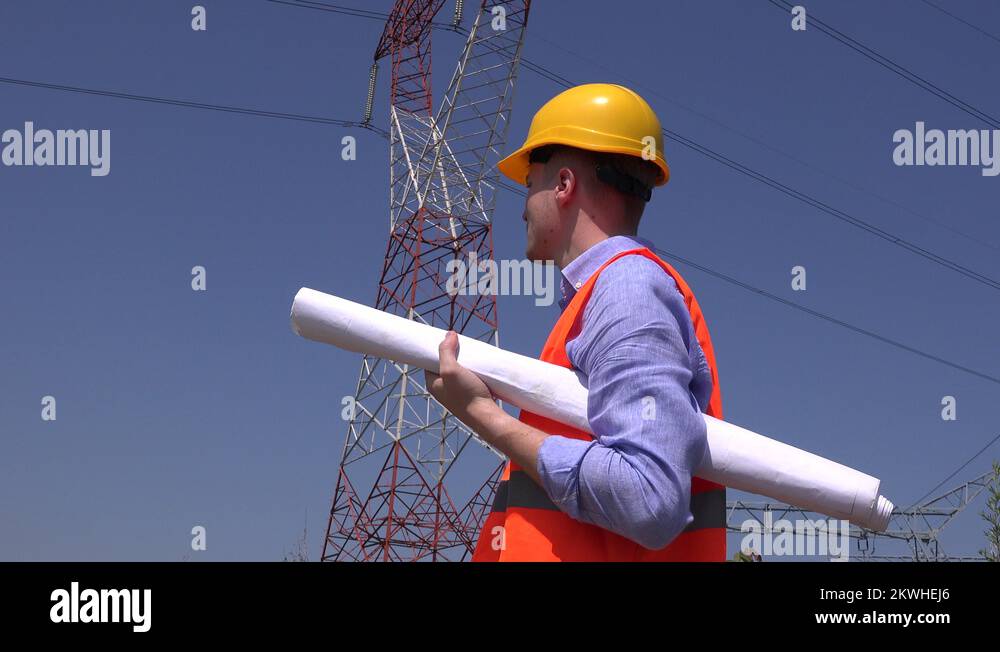 Electrician worker with energy distribution plans checking tower pillar ...