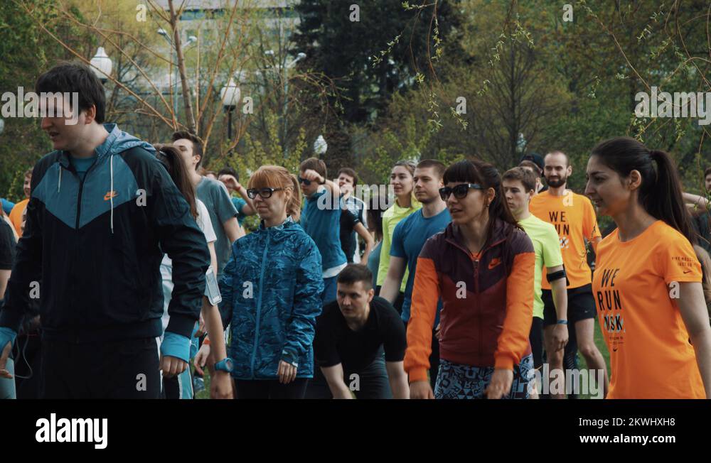 People crowd at city park repeating aerobic exercises, swoosh hands in ...
