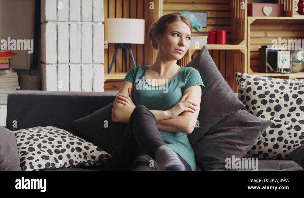 Beautiful girl sitting on the couch in the living room. She's in a bad ...