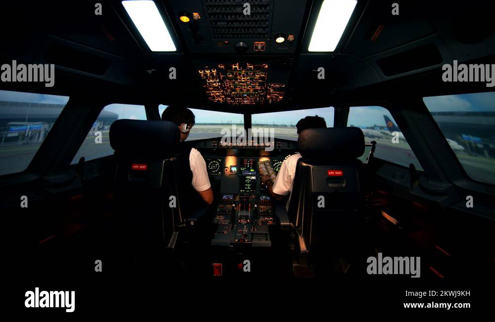 Two caucasian male pilots in the cockpit or flight deck of a passenger ...