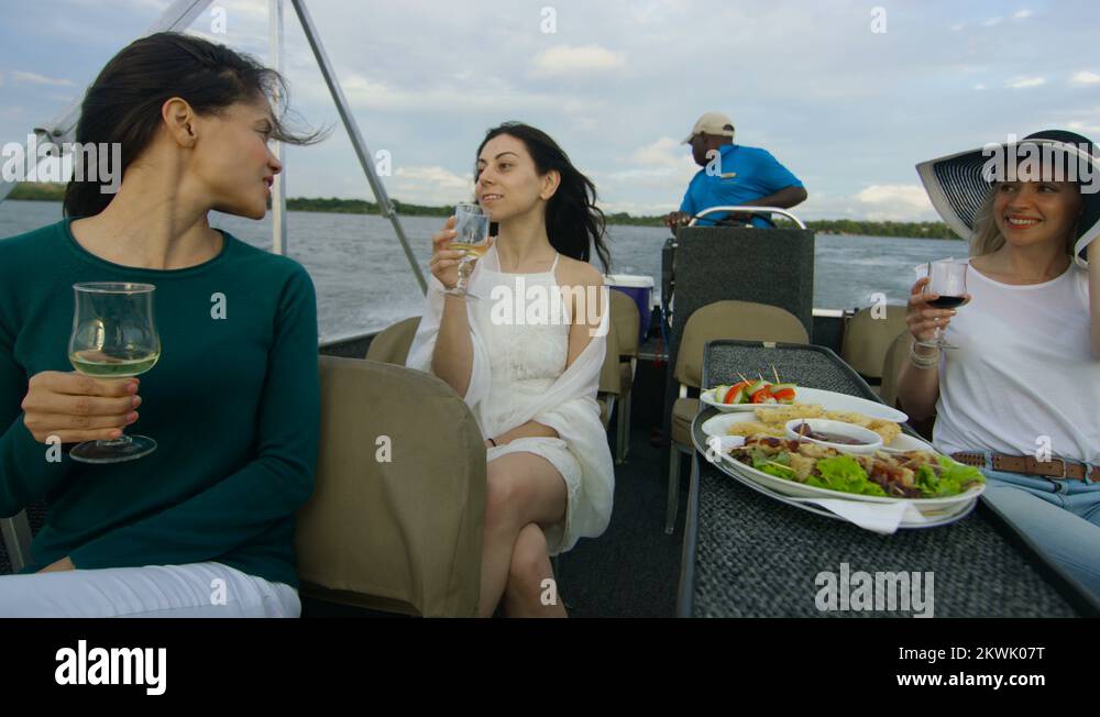 4K Friends on African vacation drinking wine on boat trip on Zambezi ...