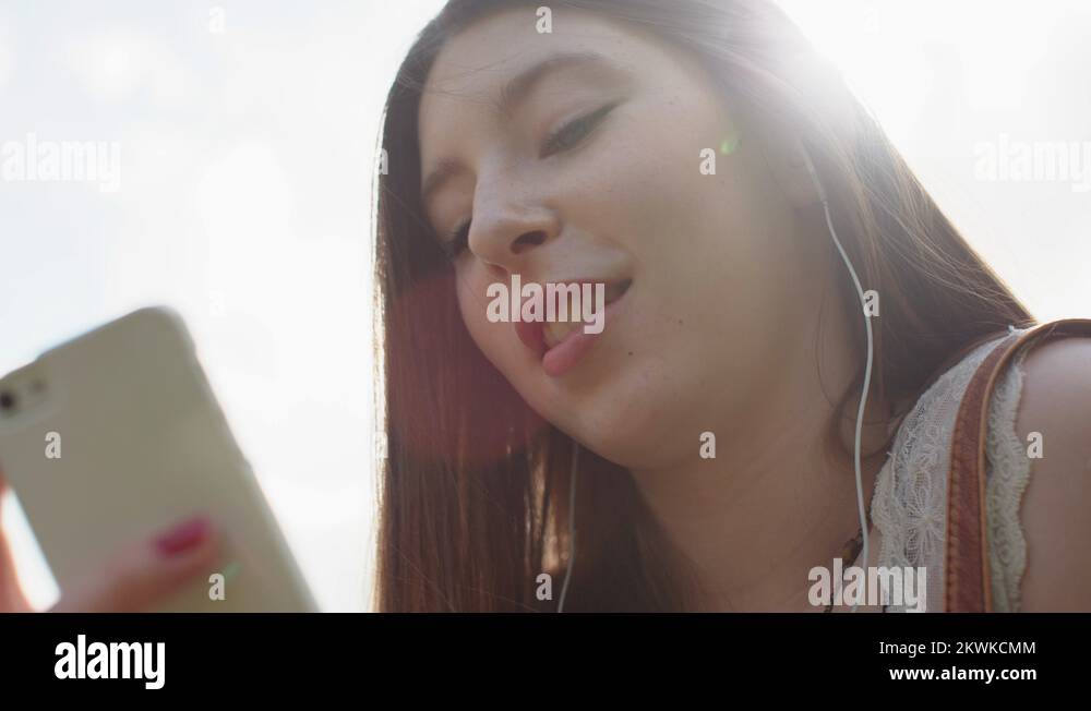 Handheld close-up of teenage girl with mobile phone singing while ...