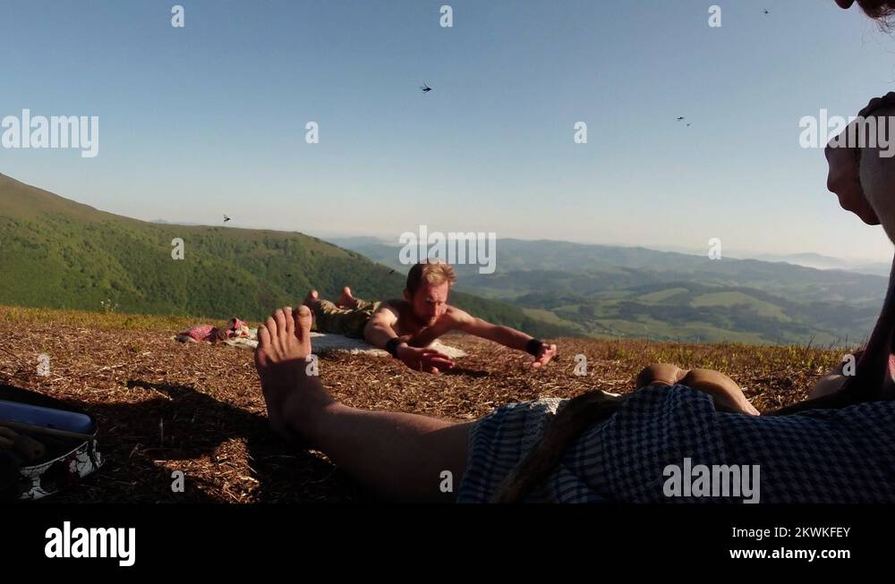 Yogi does exercises lying on his stomach in the mountains, another person does s Stock Video ...