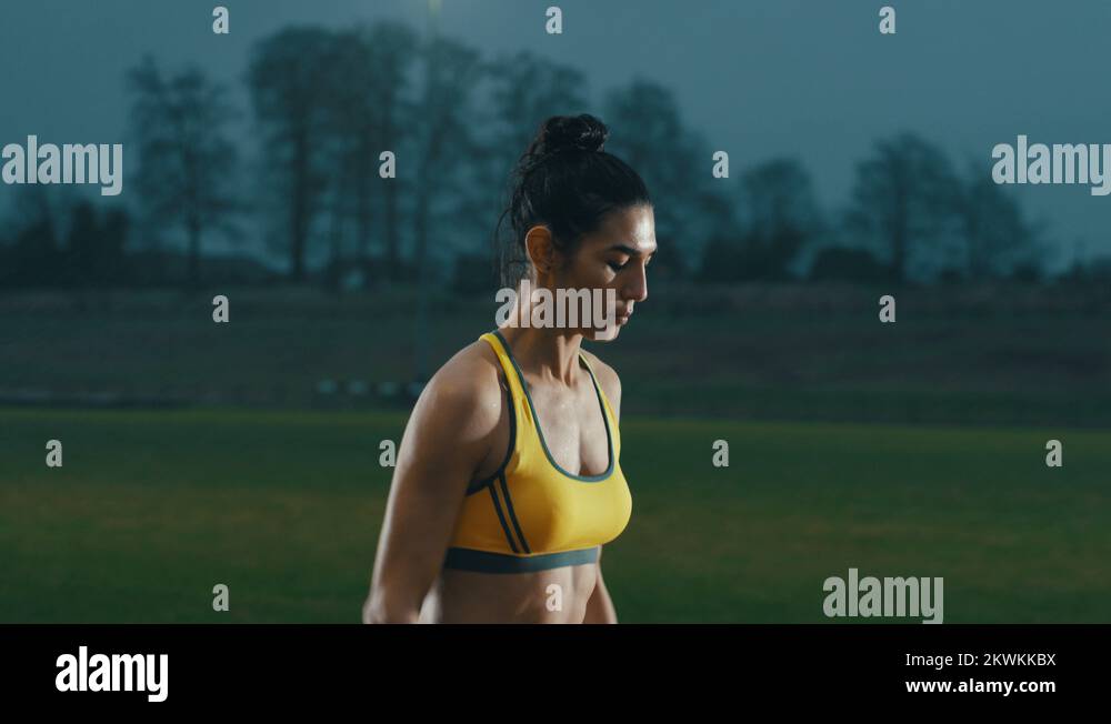 4K Female athlete at running track crouching at starting blocks before ...