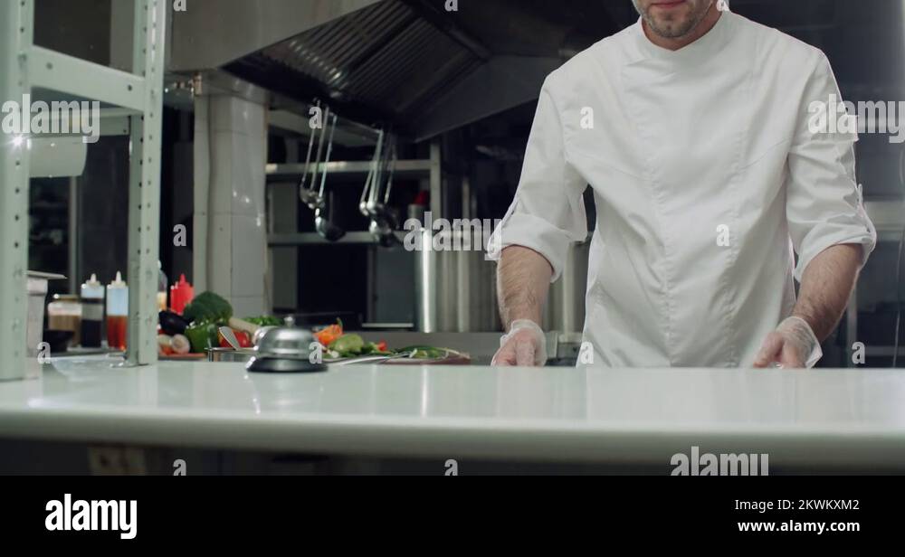 Asian chef serves a dish of meat on a plate adding the final decoration ...