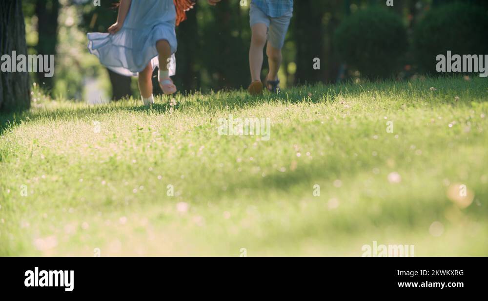 two kids,a boy and a girl running around in the garden holding hands ...