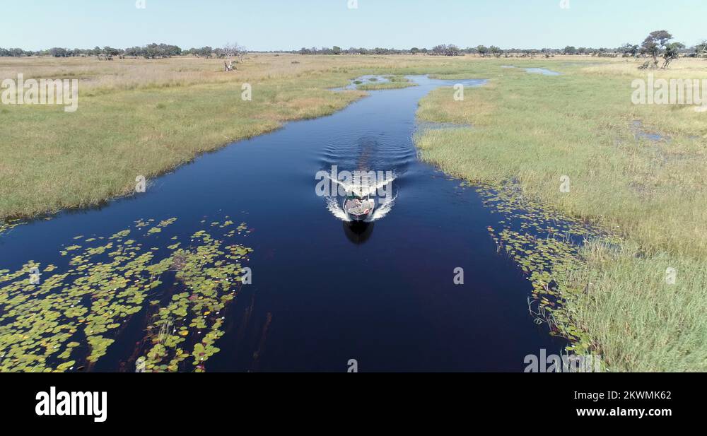 Zoom out high aerial view of a tourist boat making its way down one of ...