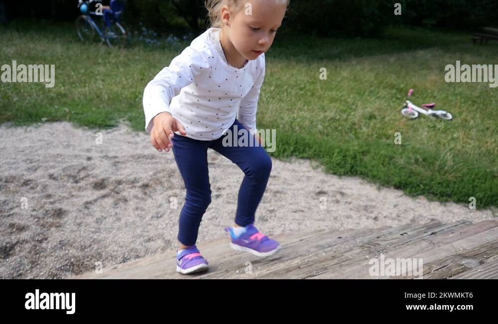 Little kid girl on park playground for children play walk up the wooden ...