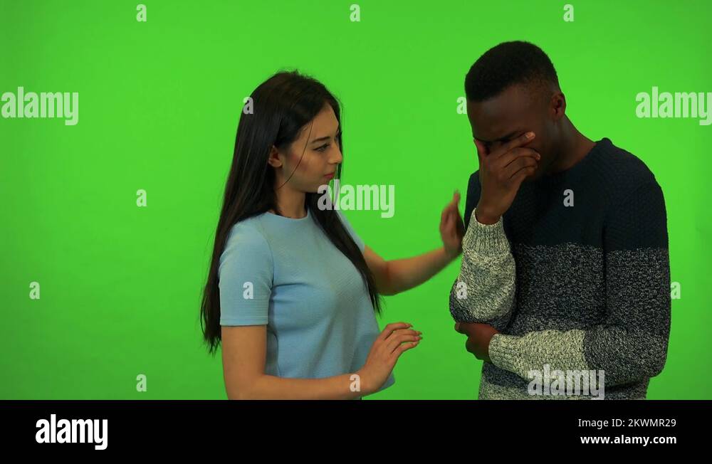 A young black man cries and a young Asian woman comforts him - green ...
