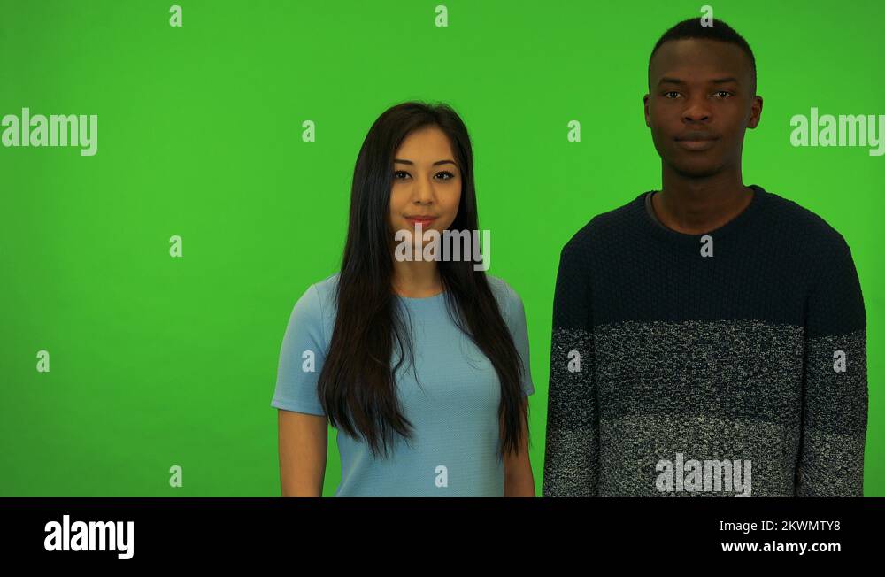 A young Asian woman and a young black man nod at the camera - green ...