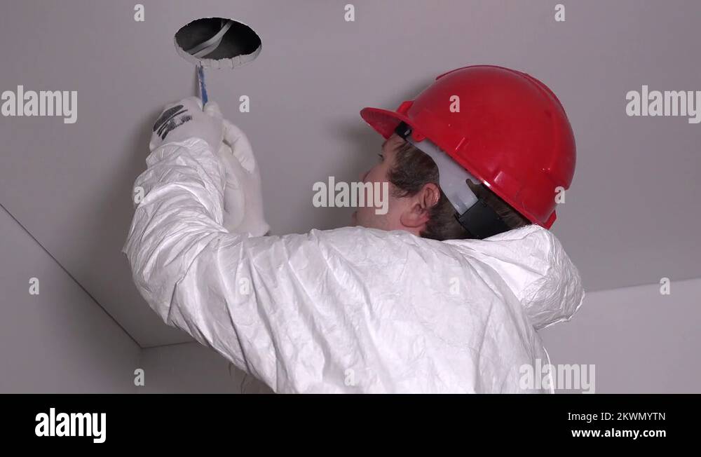 worker man on ladder cutting hole in drywall ceiling for lighting ...