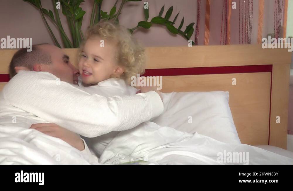 Little cute girl wake up her father sleeping and embrace hug in bed ...