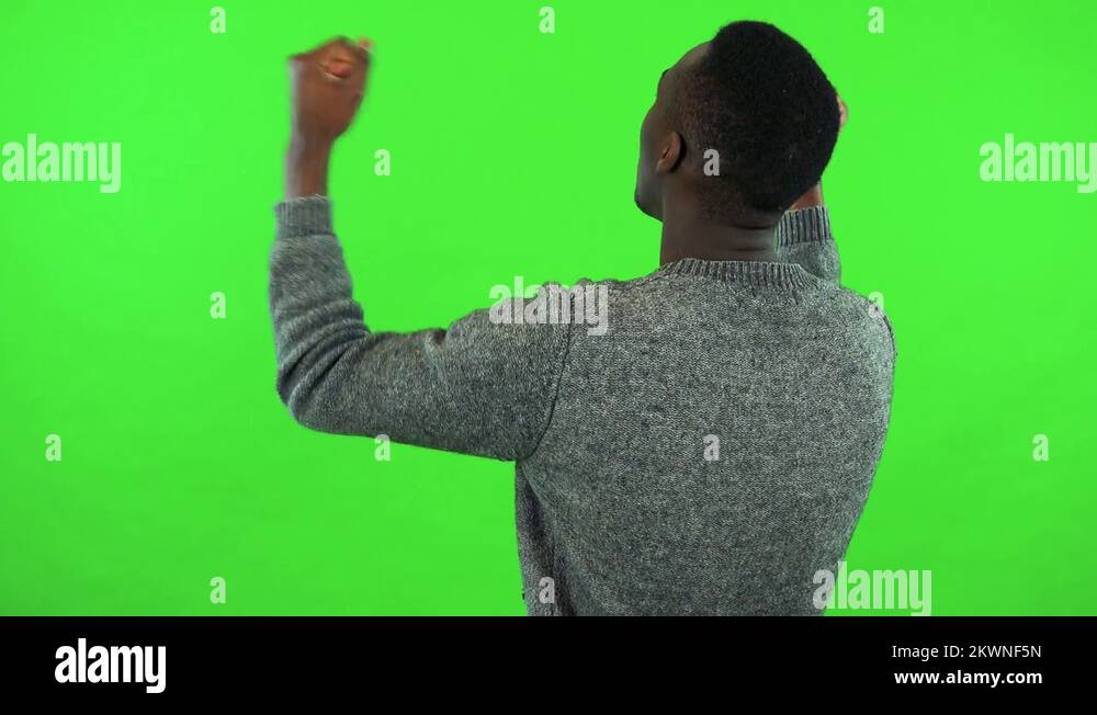 A black man cheers with his back to the camera - green screen studio ...