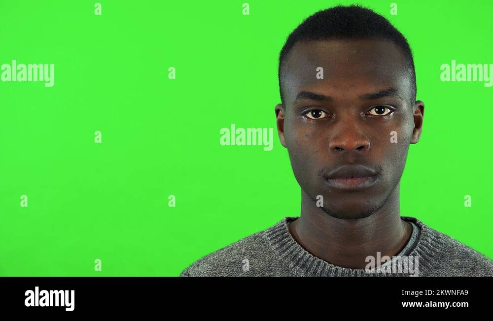 A young black man looks at the camera - face closeup - green screen ...