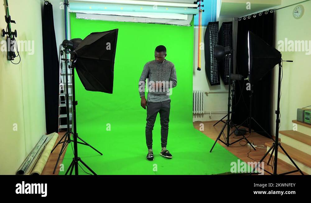 A young black man adjusts his clothes in a green screen studio Stock ...