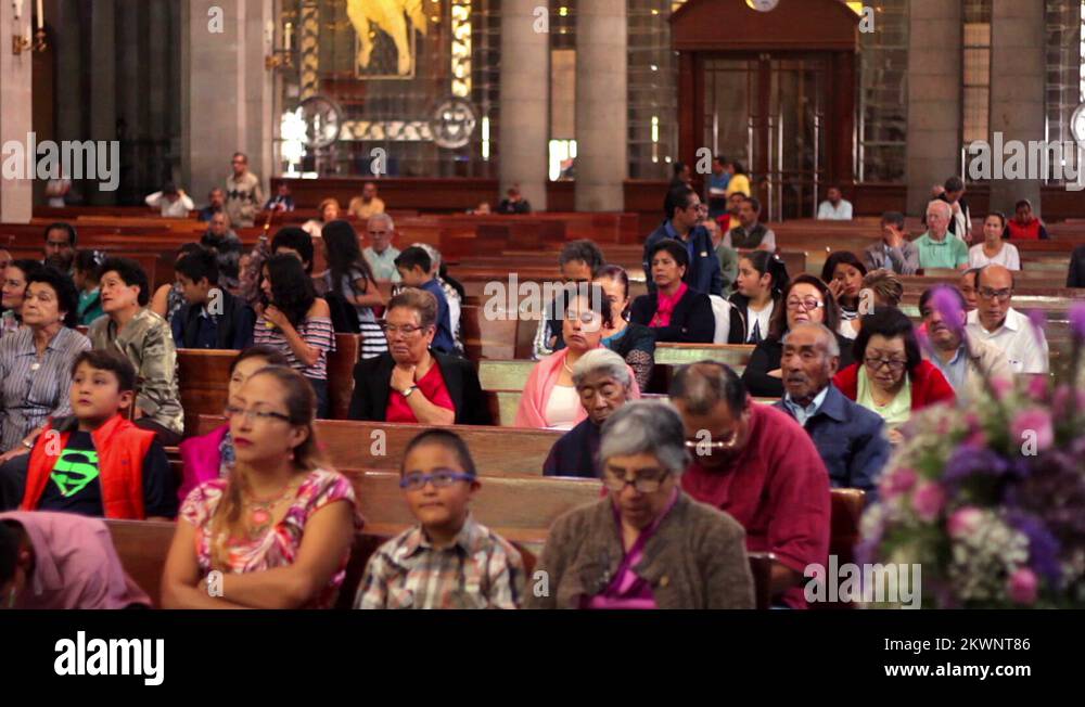 People sitting on wooden benches praying in the San Jose Cathedral ...