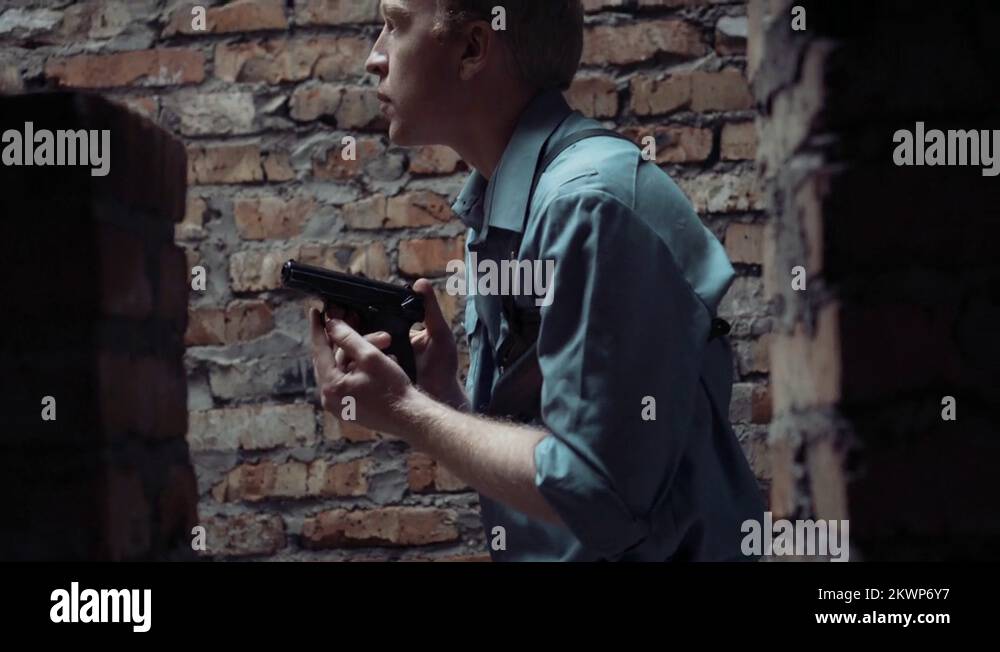 Man in a uniform climbs up the stairs basement with a gun in his hand ...