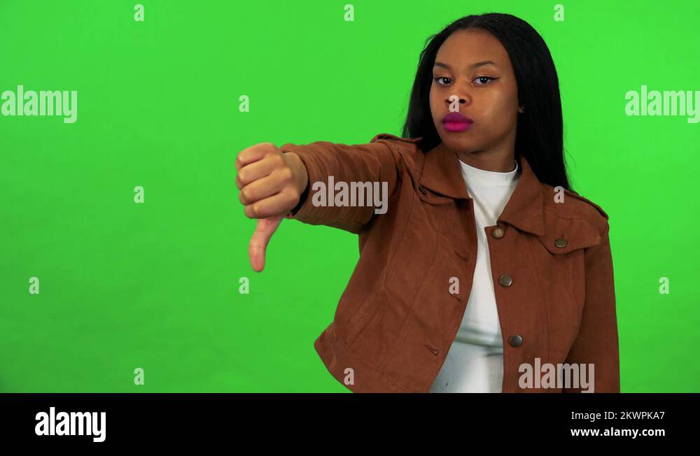 A young black woman shows a thumb down to the camera - green screen ...